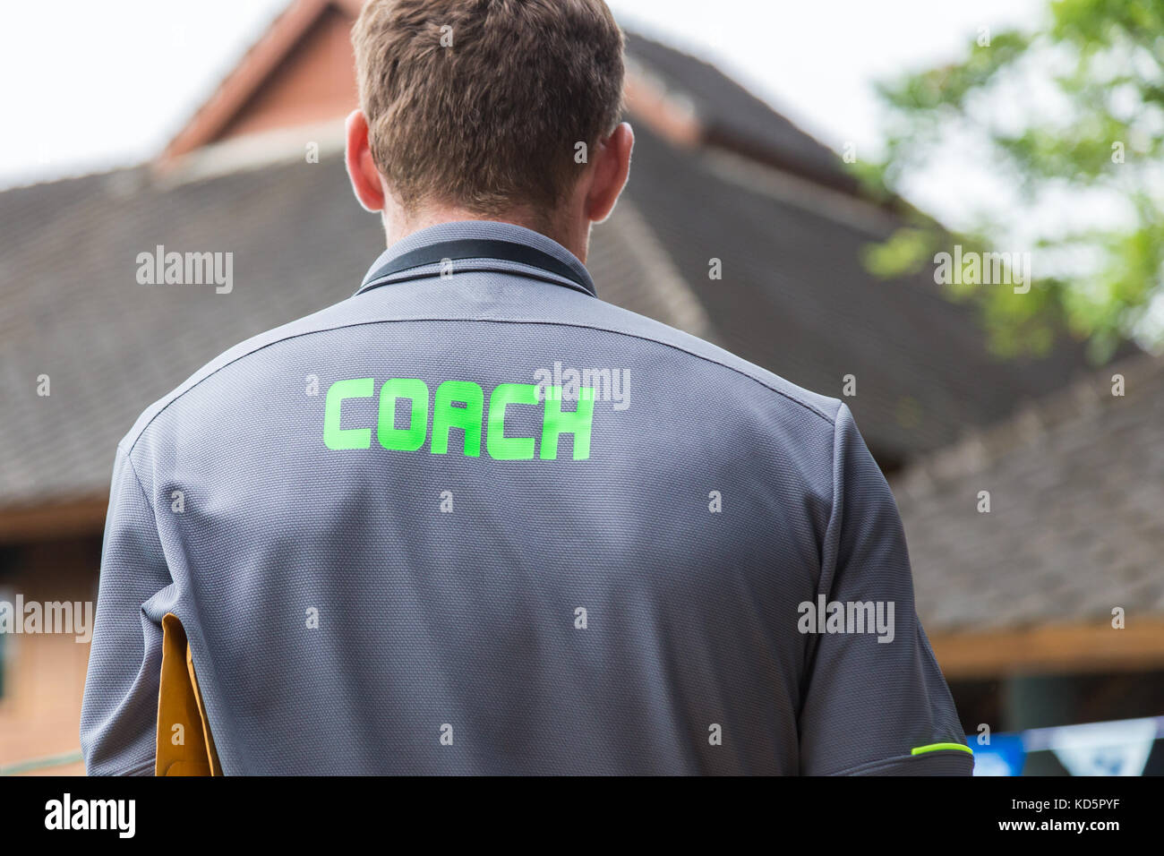 back of a male coach's grey shirt with the green word Coach written on ...