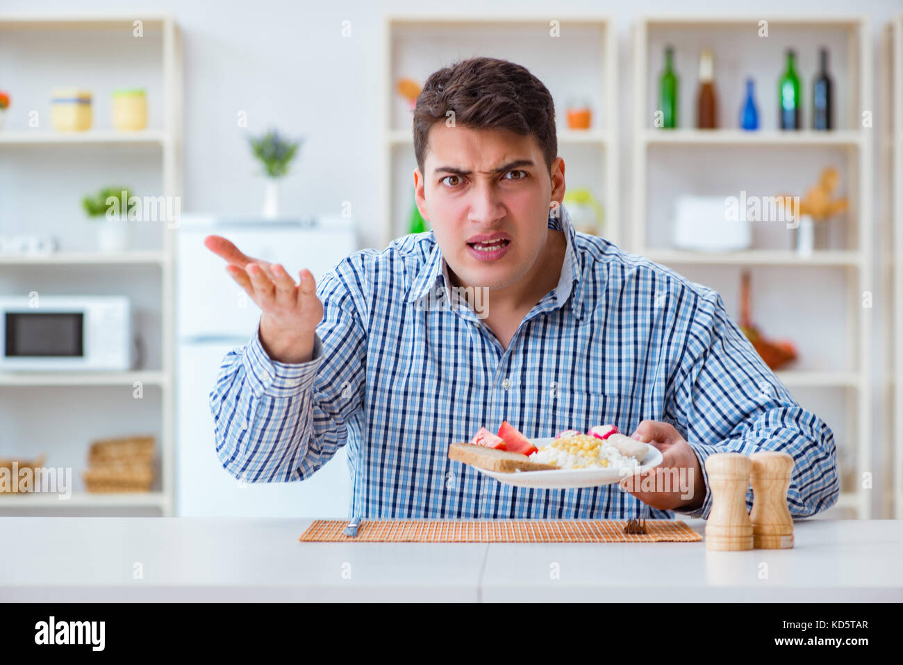 Young husband eating tasteless food at home for lunch Stock Photo - Alamy
