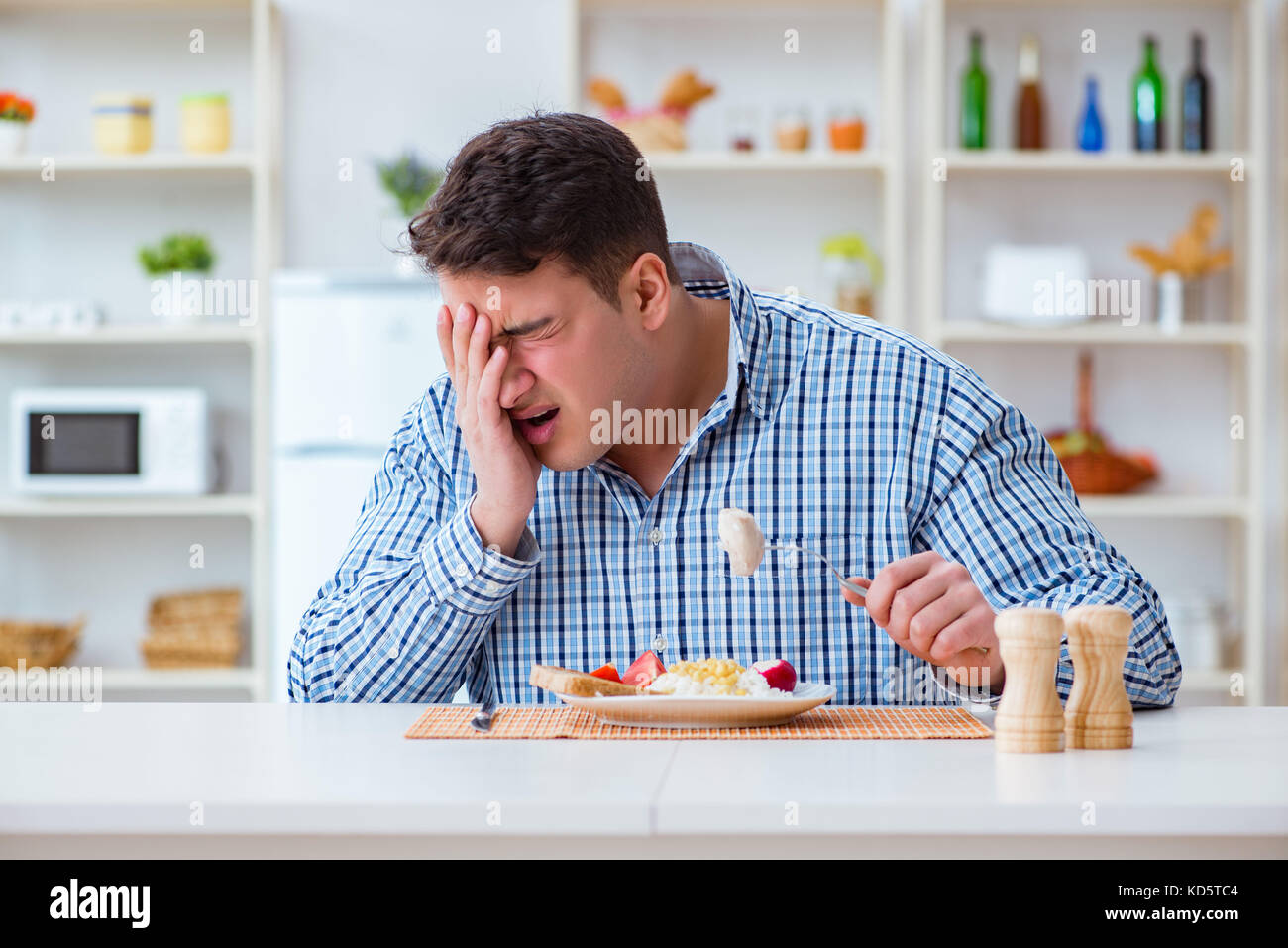 Man eating tasteless food at home for lunch Stock Photo - Alamy