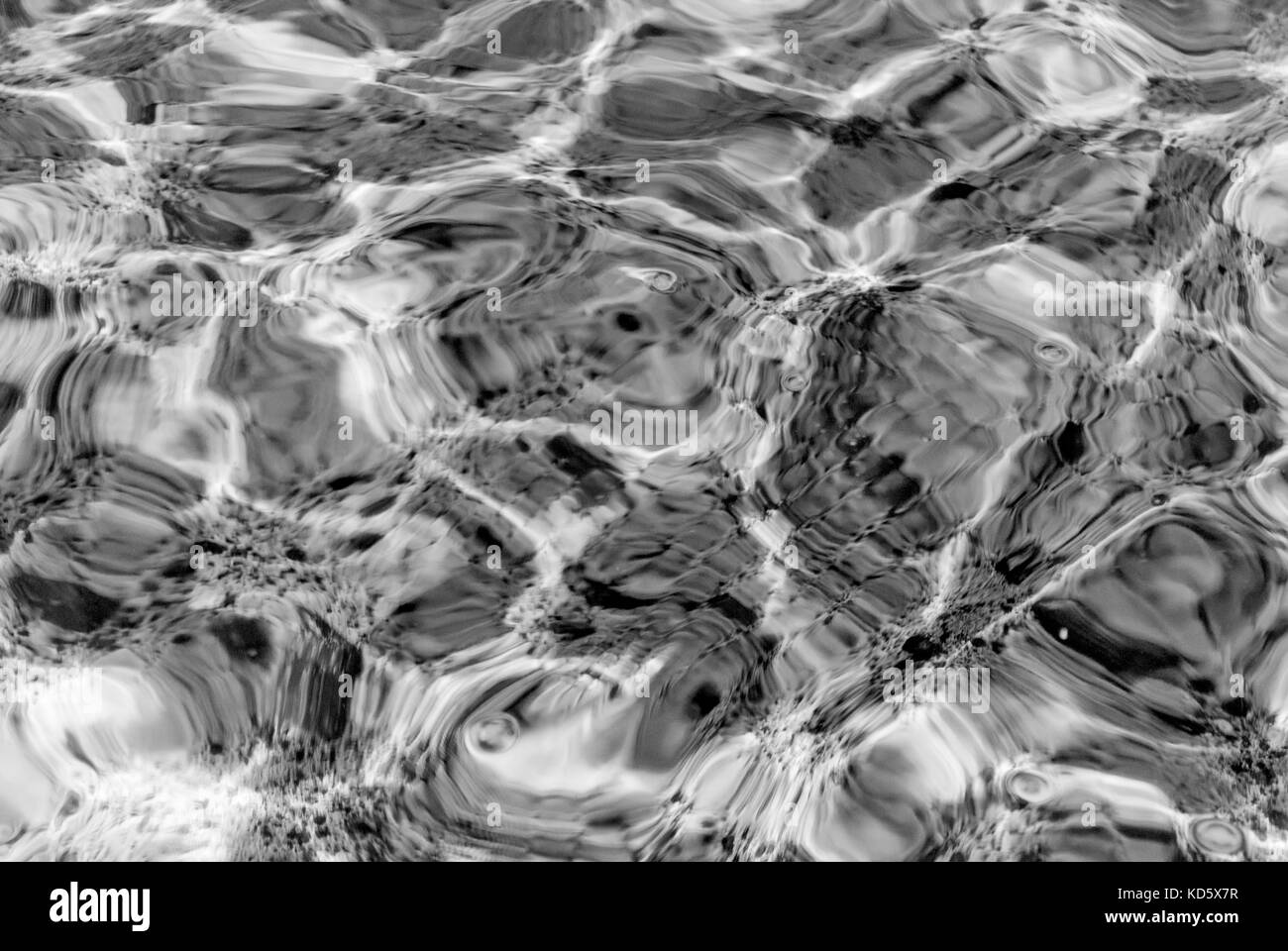 Refraction of light in clear water with small waves. Black and white ...
