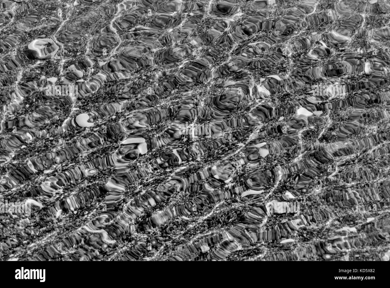 Refraction of light in clear water with small waves. Black and white ...