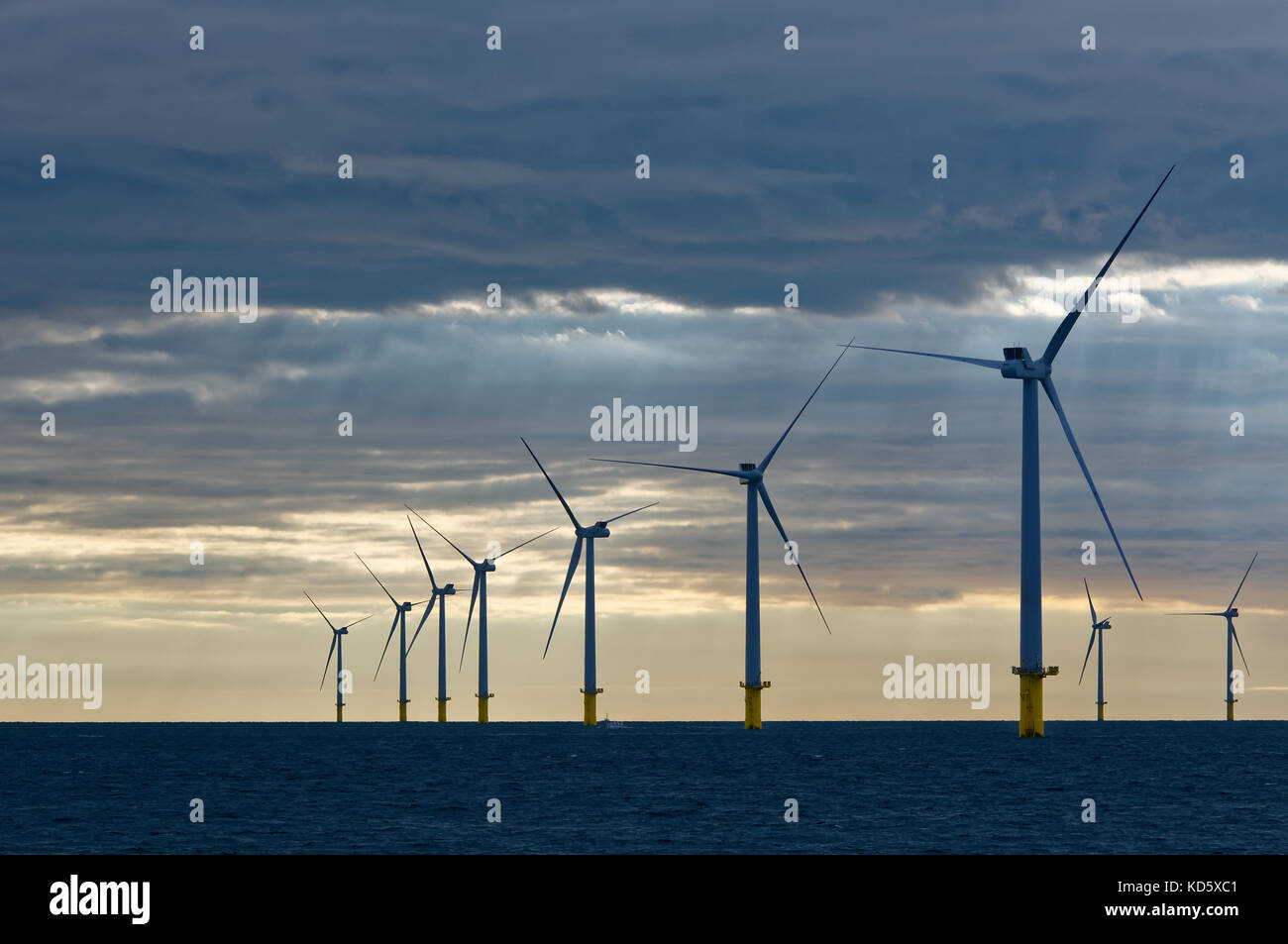 Shafts of light illuminate wind turbines at sunset at the Rampion ...