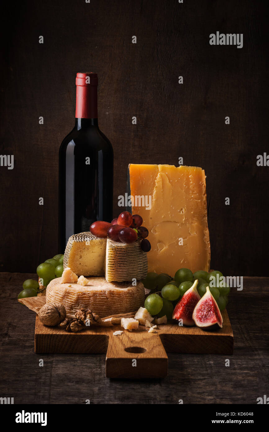 Dark still life with cheese board, fruits and wine Stock Photo - Alamy