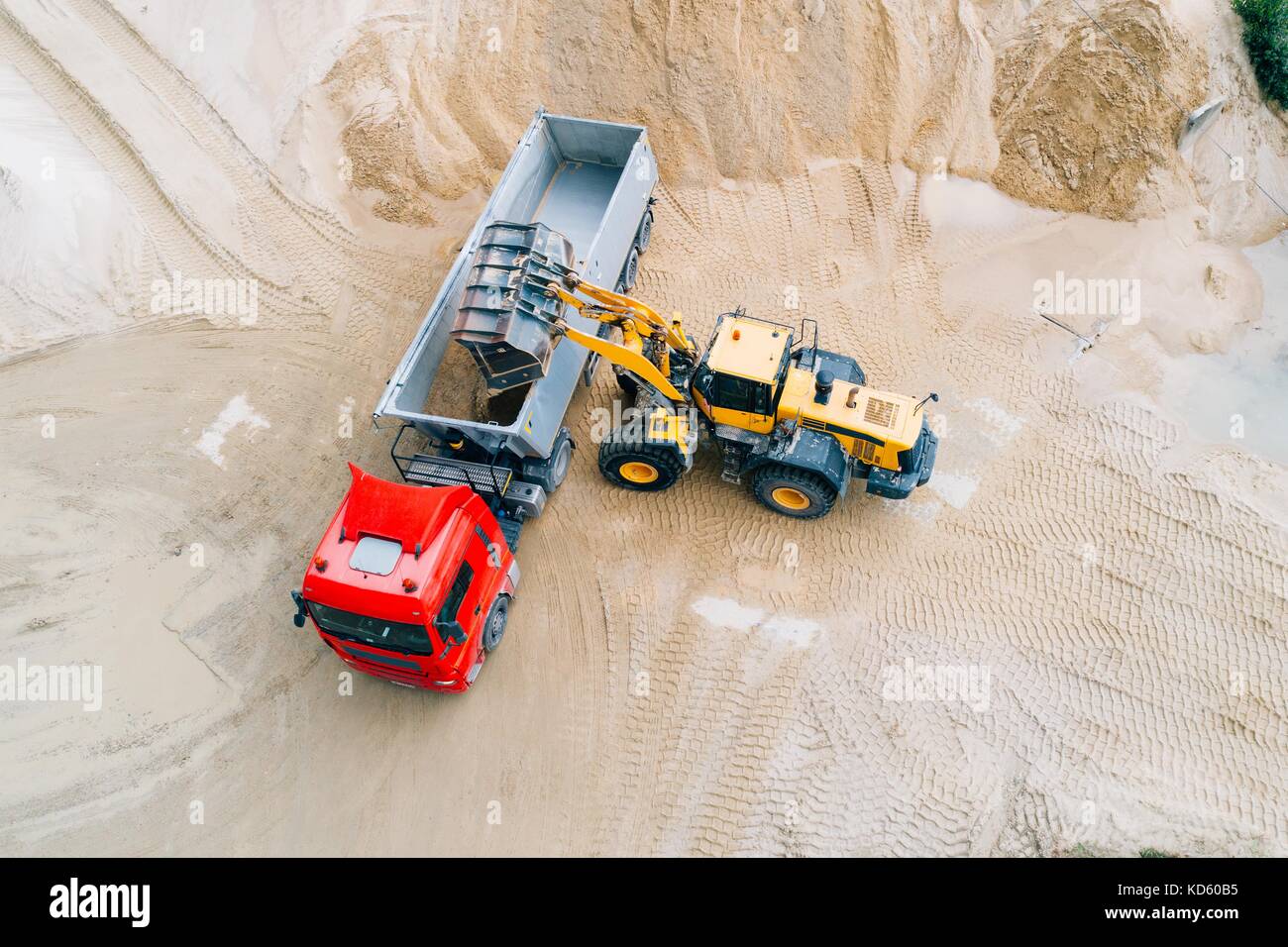 Yellow wheel loader loading sand on dumper truck. Sand quarry Stock ...