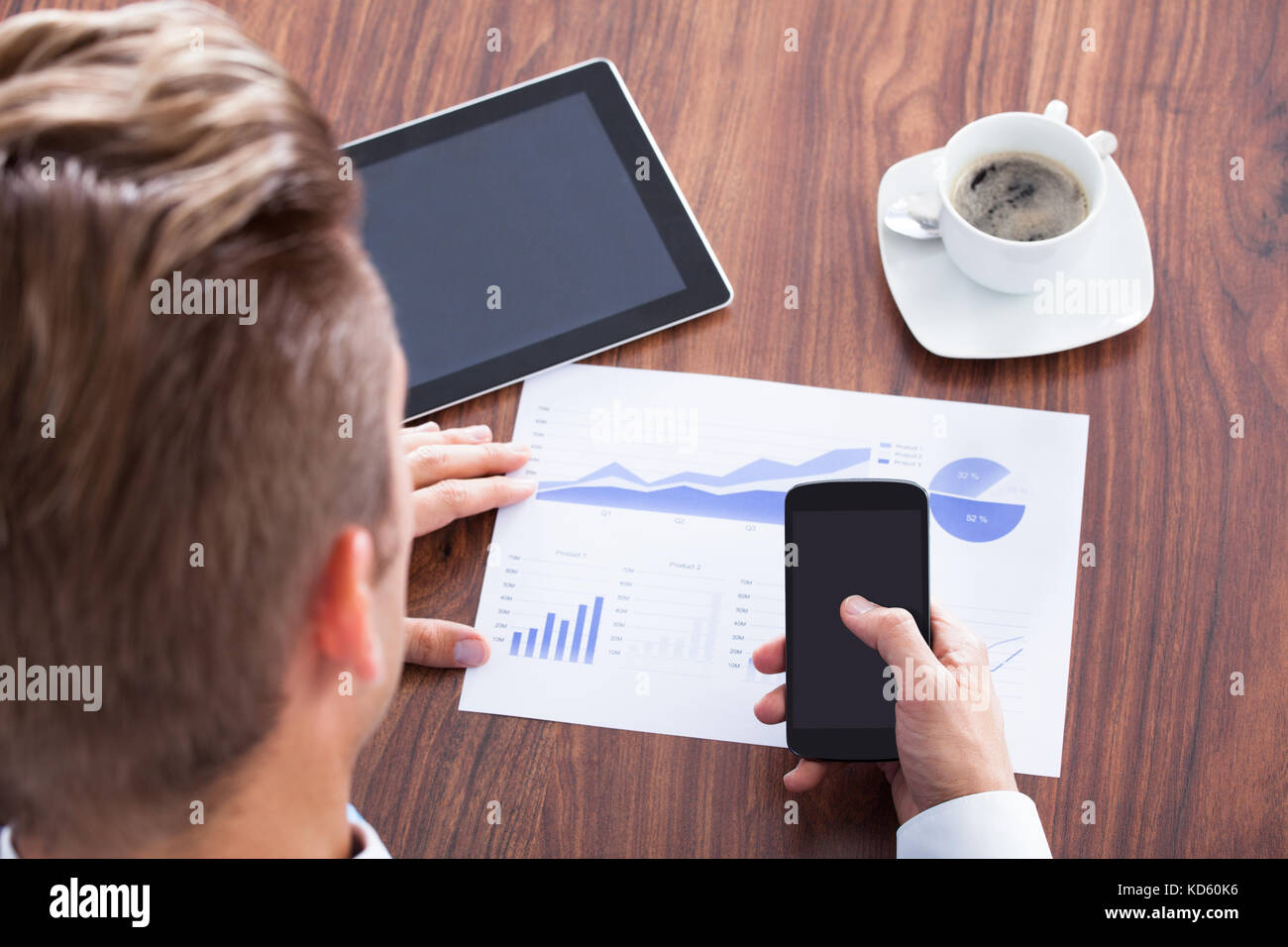Businessman Holding Cell Phone And Analyzing Graph In Office Stock ...