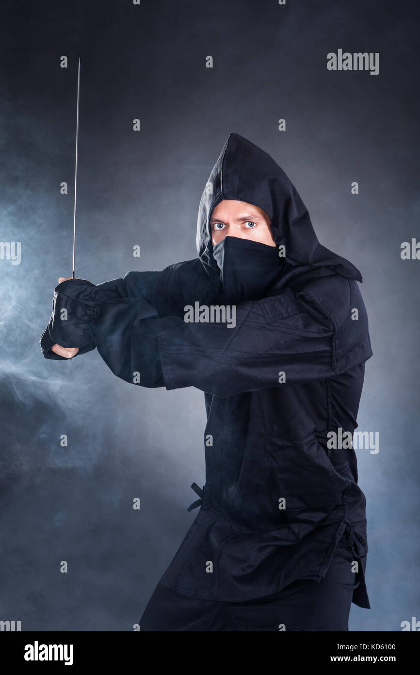 Portrait Of Male Ninja In Black Costume Holding Sword Stock Photo - Alamy