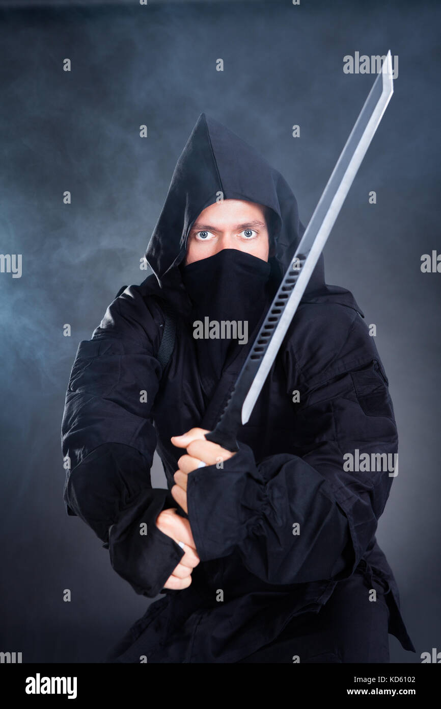Portrait Of Male Ninja In Black Costume Holding Sword Stock Photo - Alamy