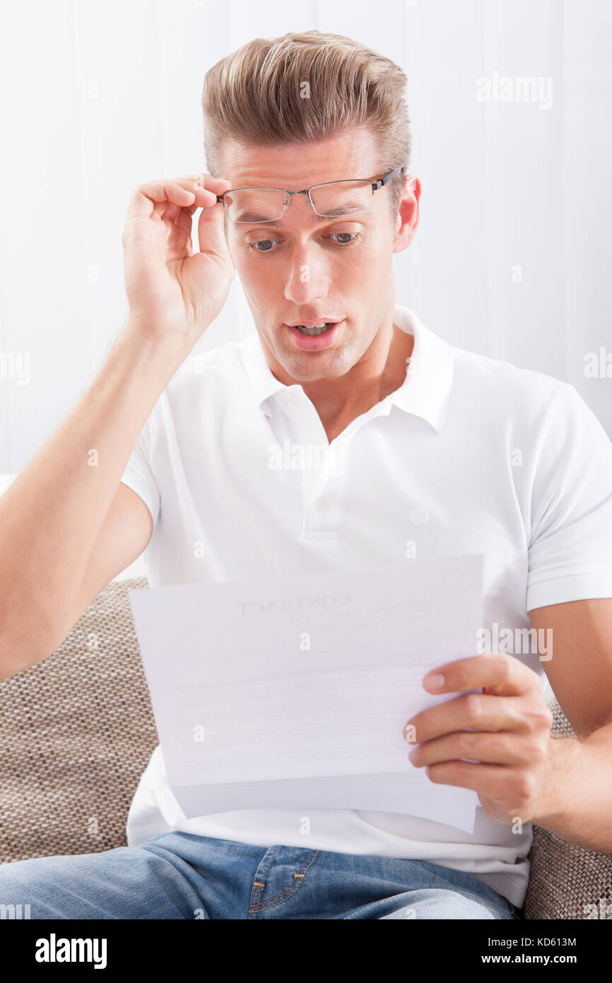 Shocked Young Man Reading Paper Holding In Hands Stock Photo - Alamy