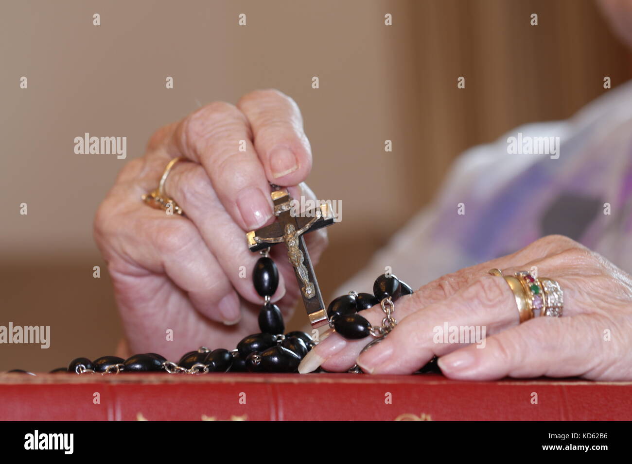 An elderly woman praying the rosary on top of her bible Stock Photo - Alamy