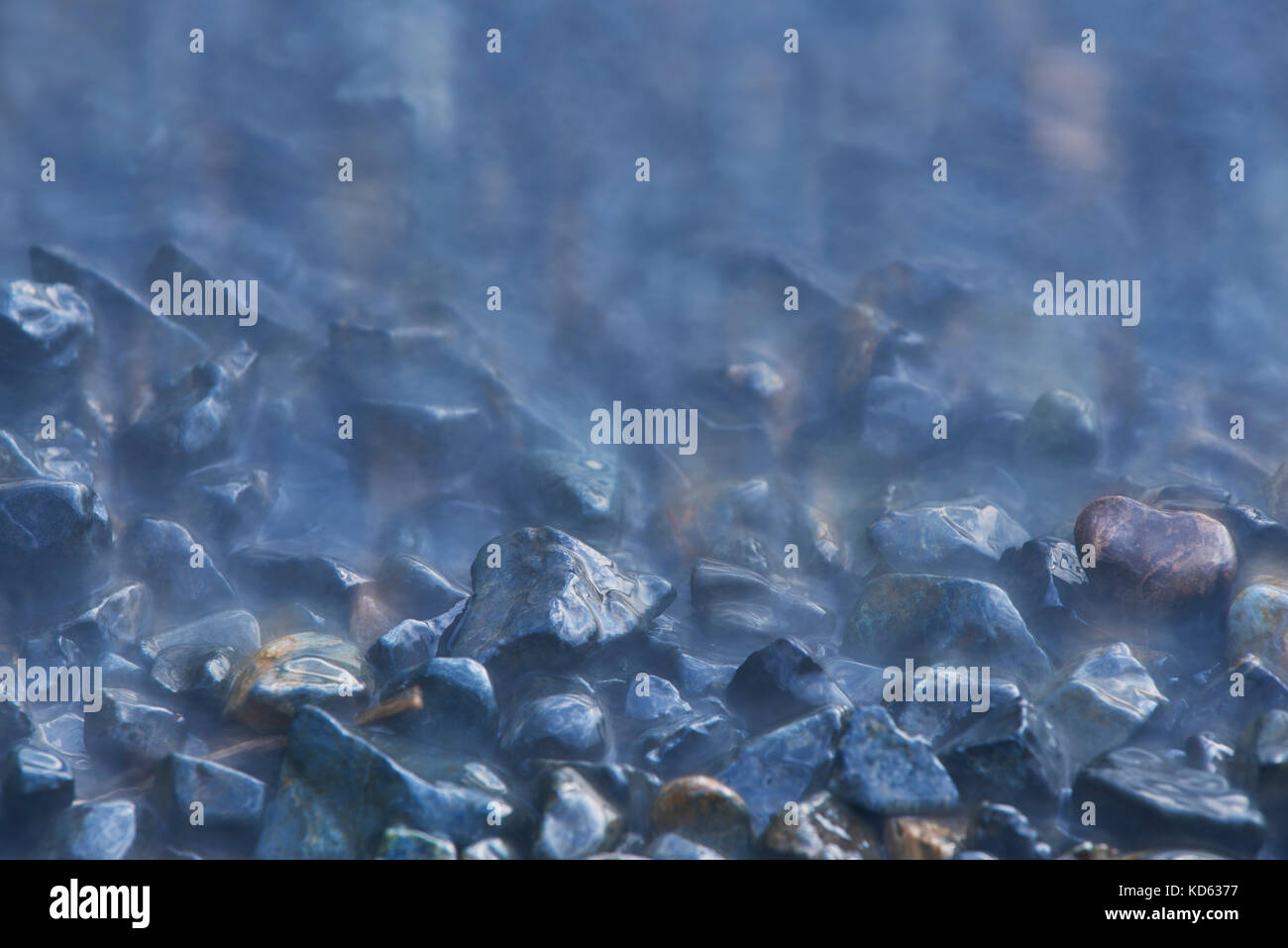 Long exposure of black rocks in the water Stock Photo - Alamy