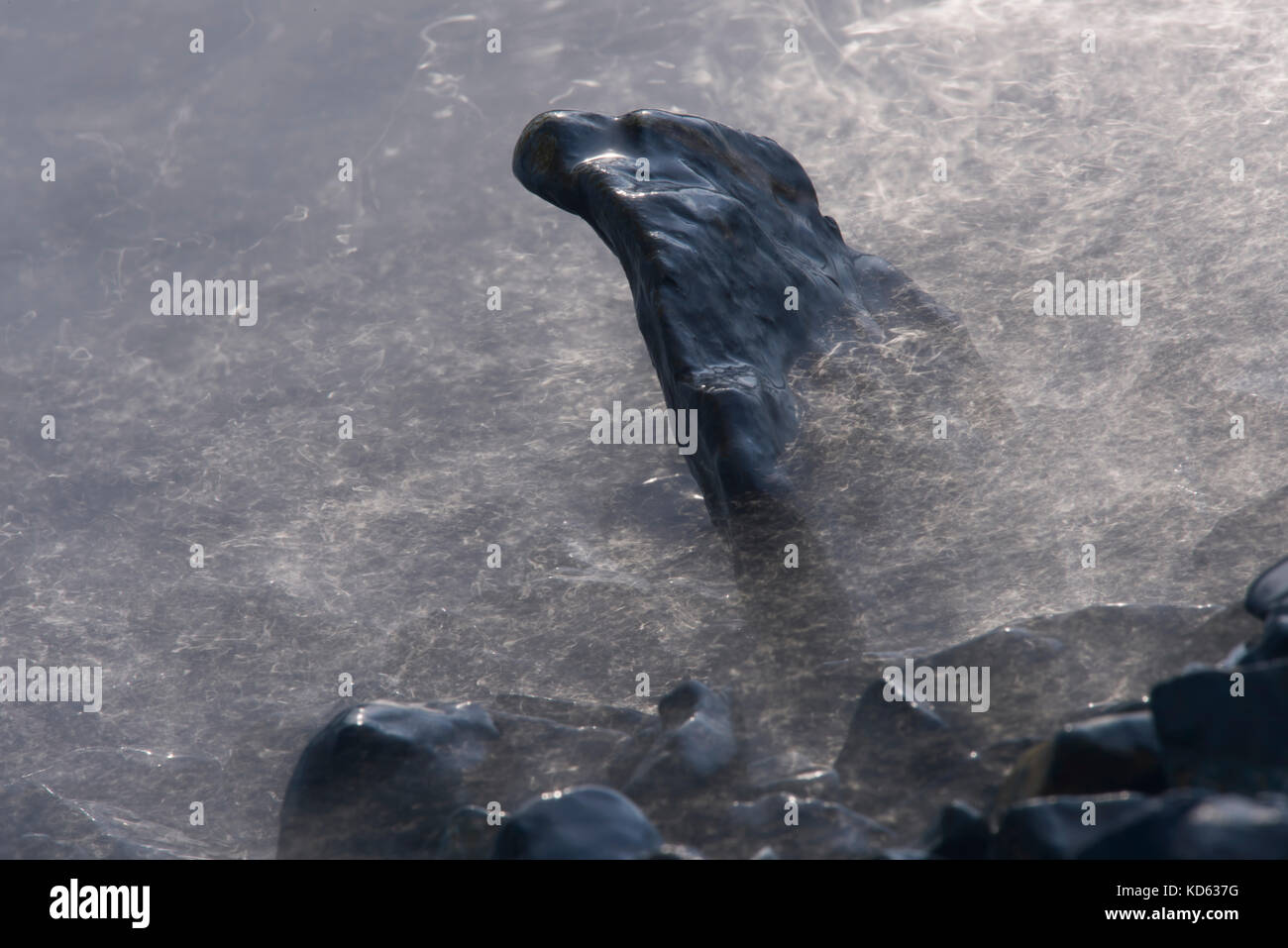 Long exposure of black rocks in the water Stock Photo - Alamy