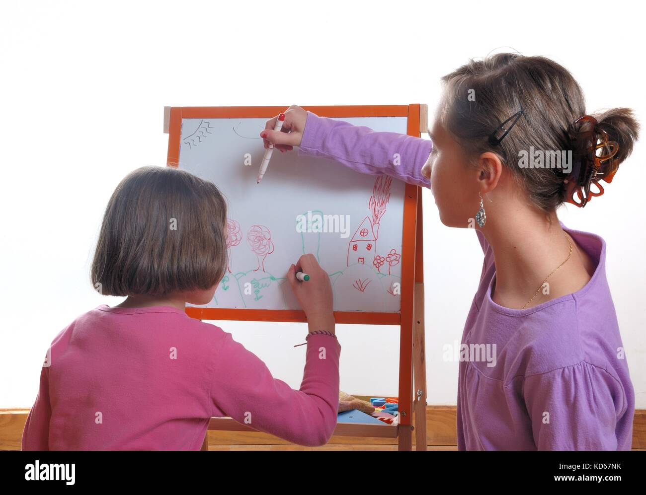 Youngs girls drawing on the white board Stock Photo - Alamy