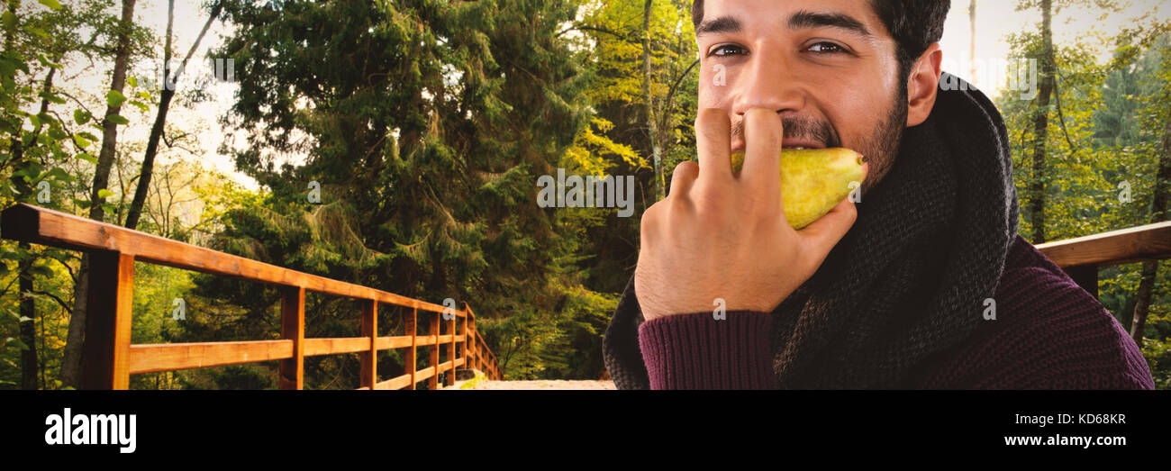 Portrait of man eating pear against bridge with railings leading ...