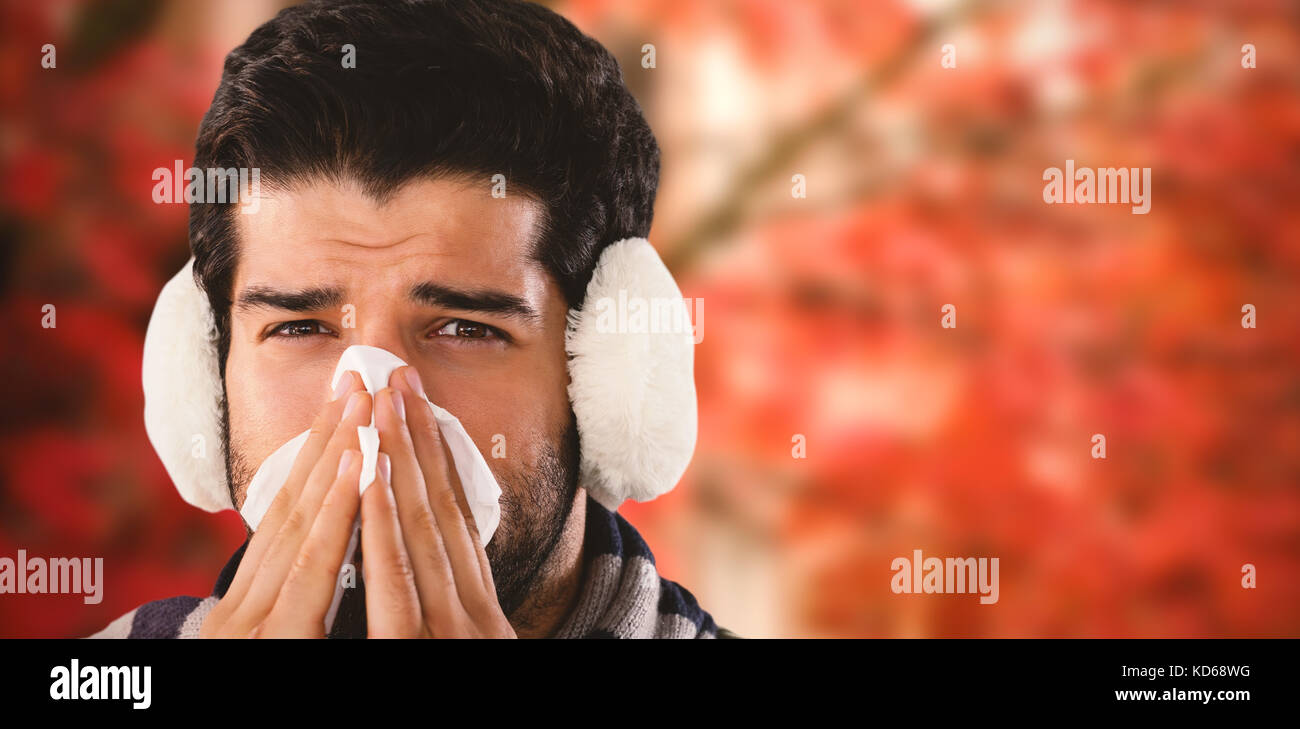 Close-up portrait of man blowing nose with tissue paper against low ...