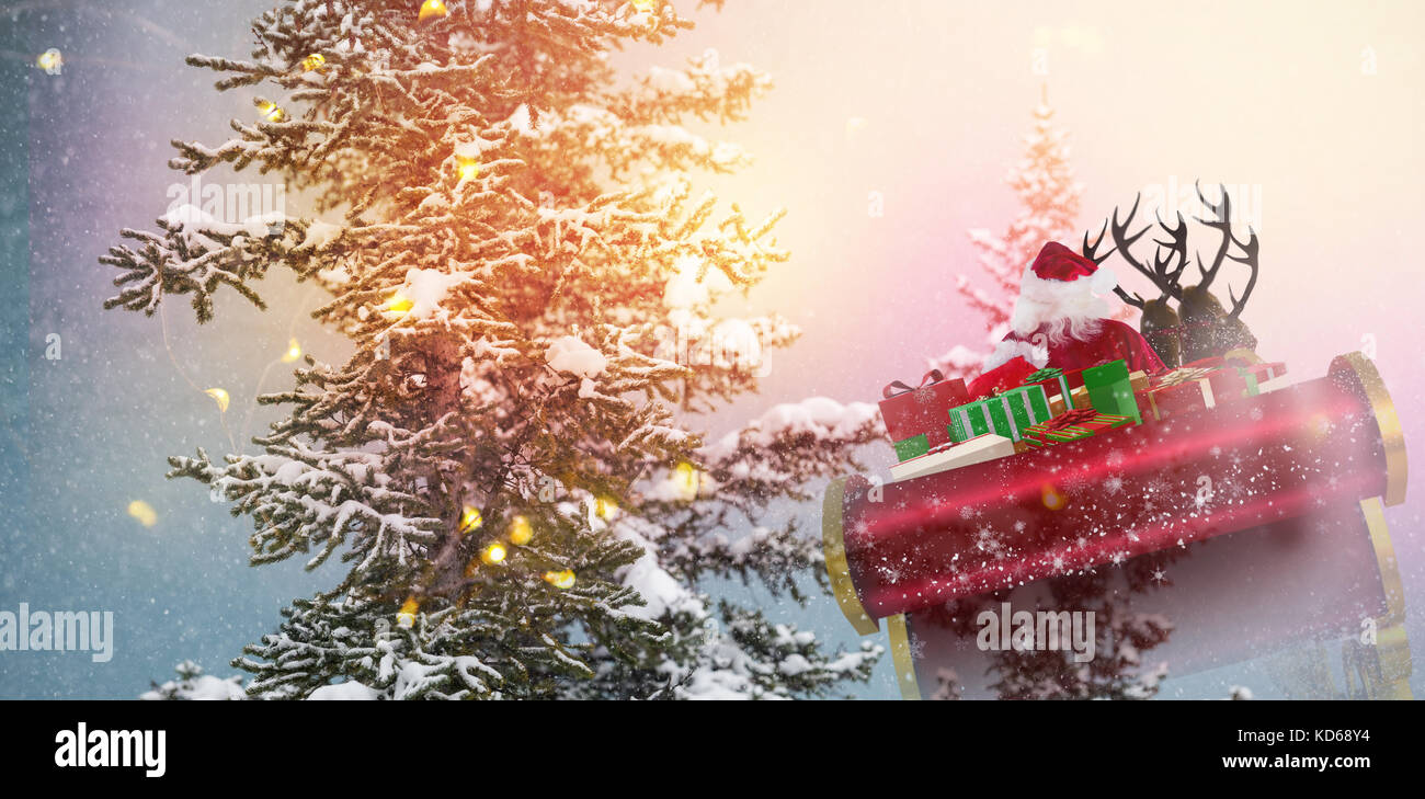 Santa flying his sleigh against snow covered trees during winter Stock ...