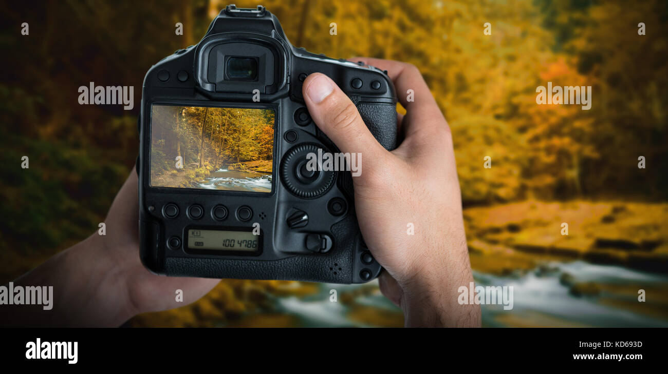 Cropped image of hands holding camera against autumn scene Stock Photo ...