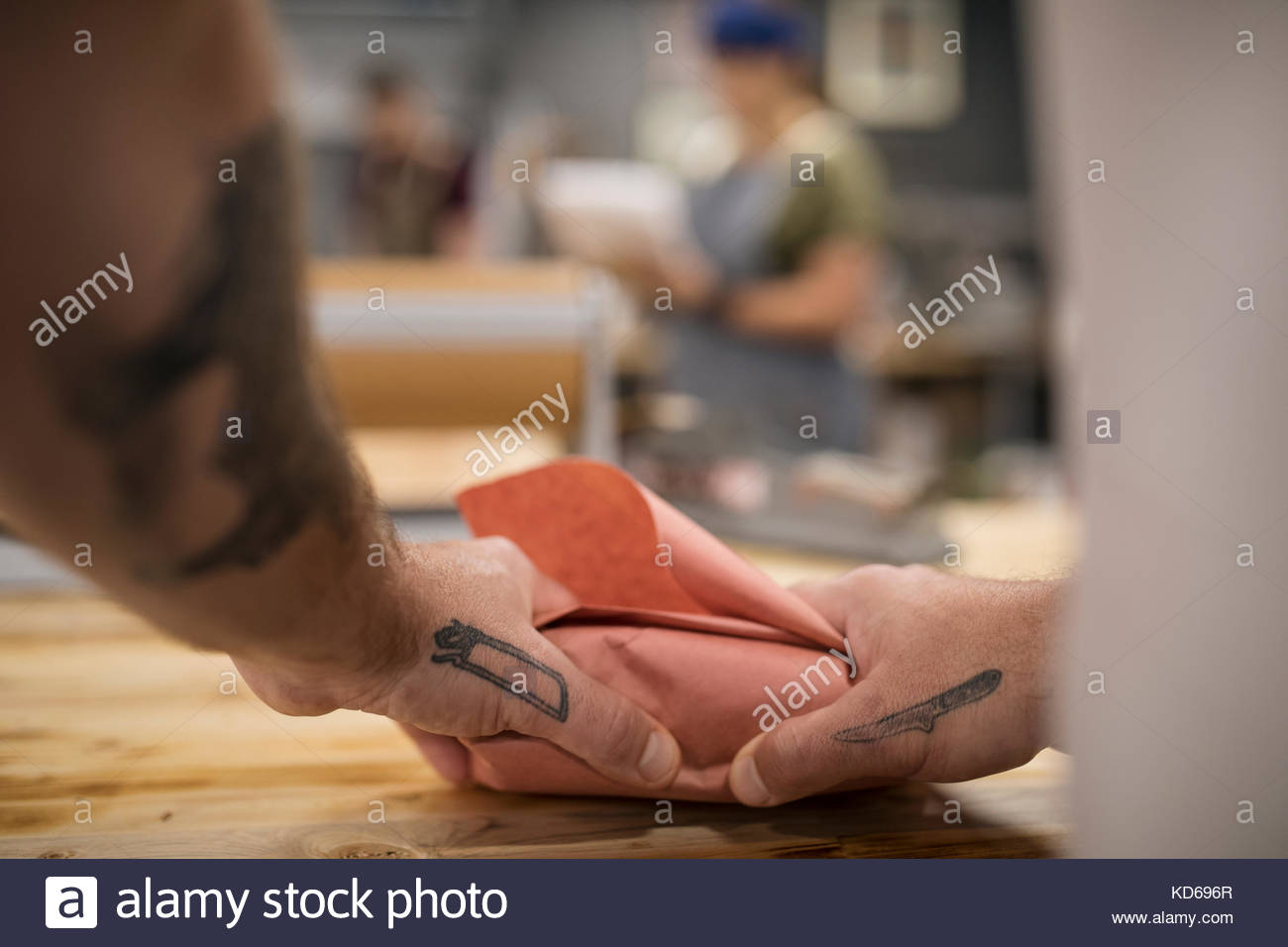 Male butcher with tattooed thumbs wrapping meat in butcher Stock Photo ...