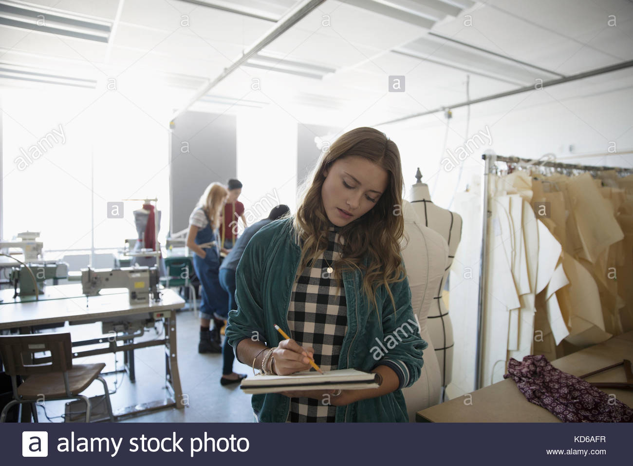 Female fashion design student sketching in notebook in studio Stock ...