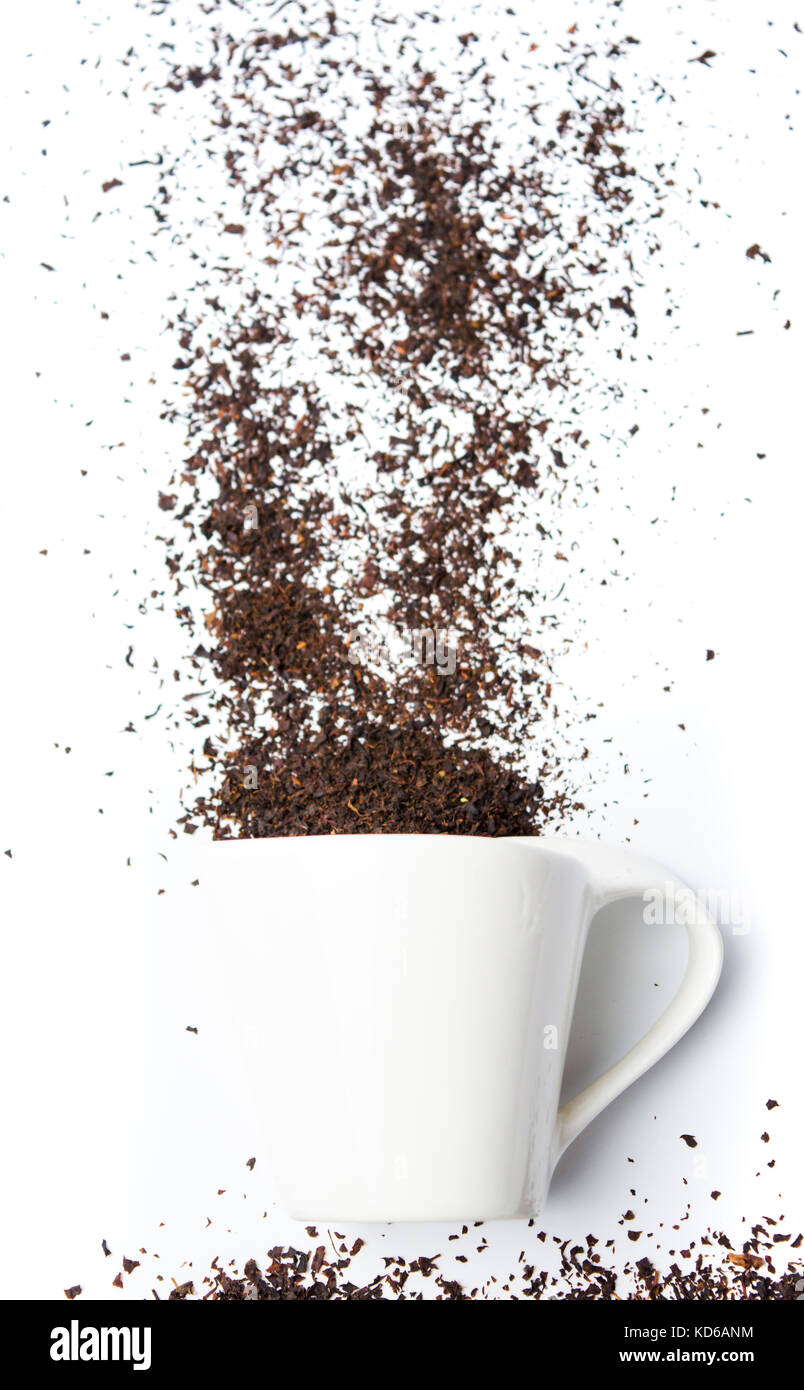 Black tea grains falling from a teacup on white Stock Photo - Alamy