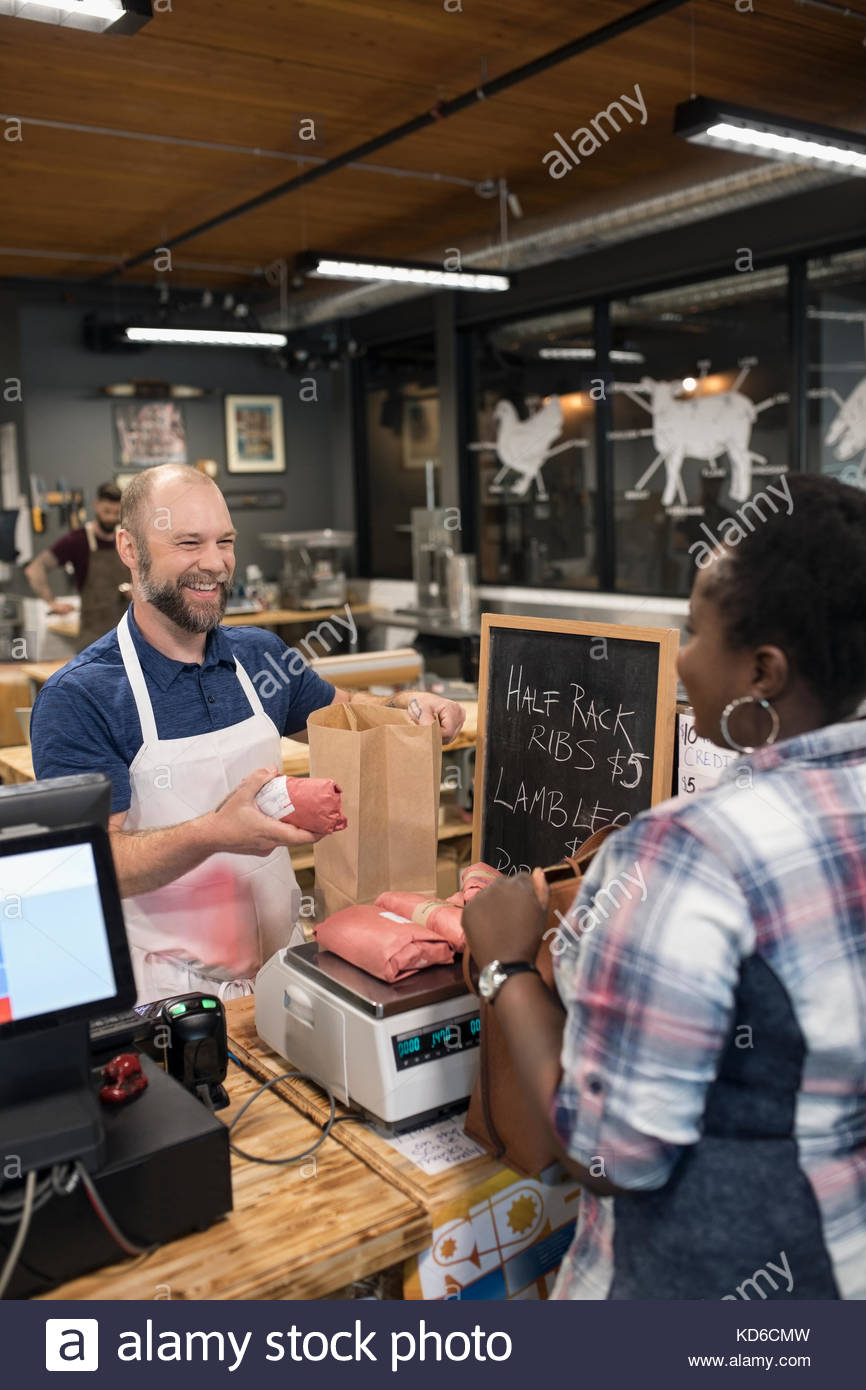 Smiling butcher helping customer at counter in butcher Stock Photo - Alamy