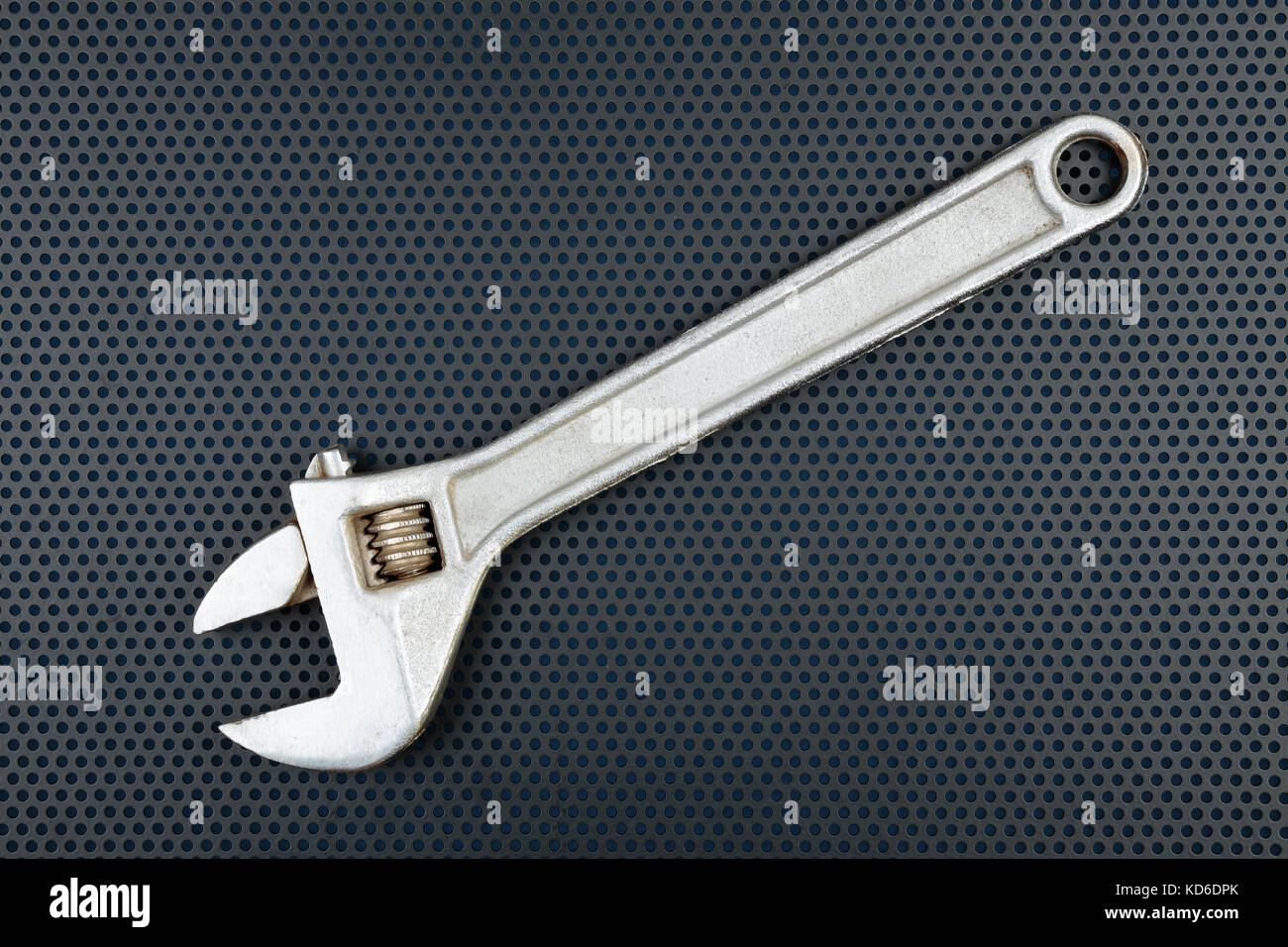 Adjustable wrench on a metallic background with perforation of round ...