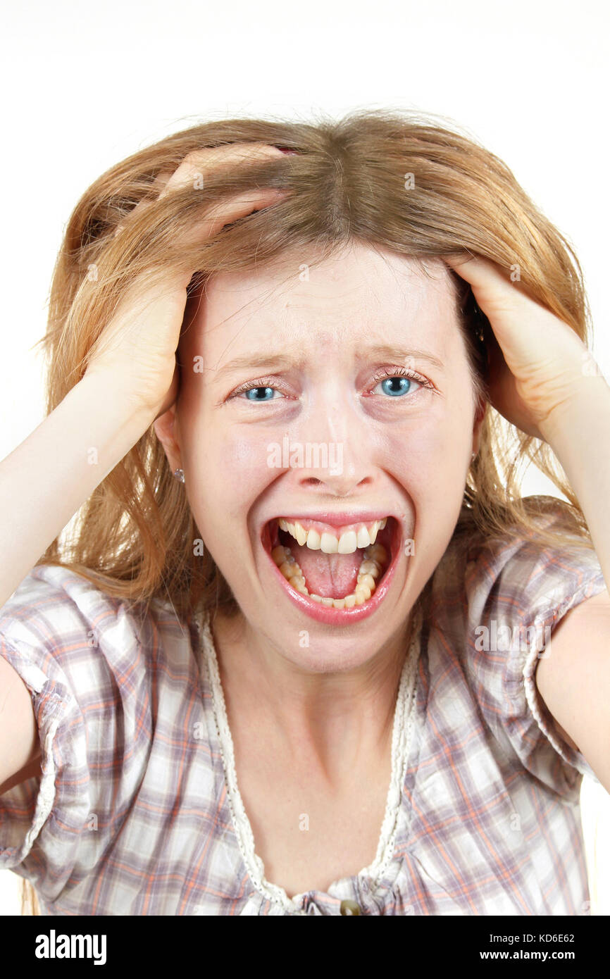 Young woman screaming in agony with mouth wide open holding head Stock ...