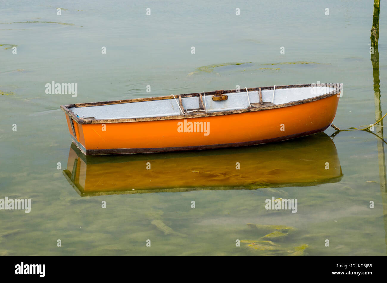 Orange wooden boat moored on calm water at low tide Stock Photo - Alamy