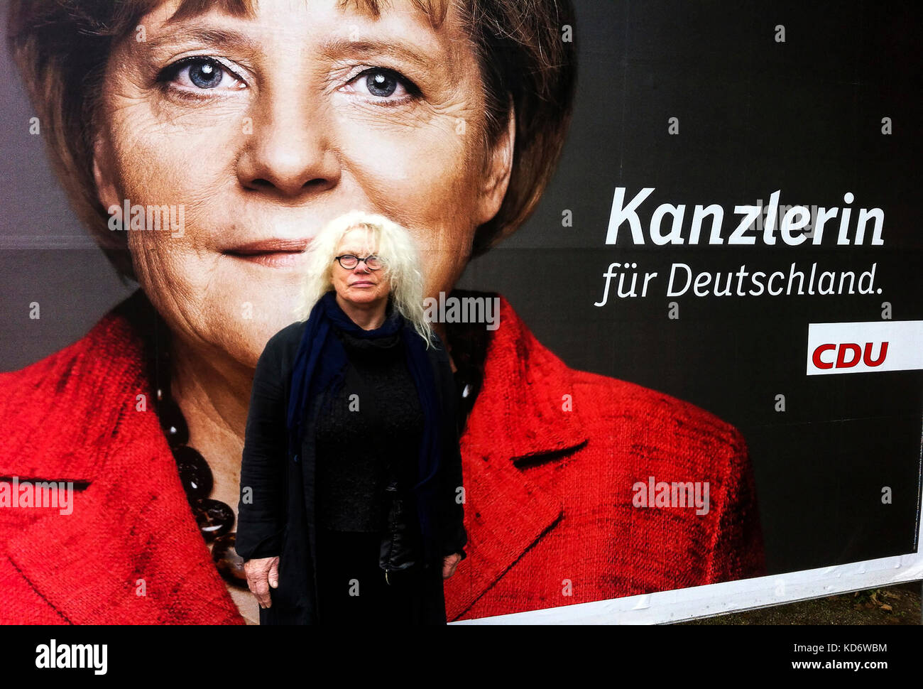 a woman stand in front of a poster depicting Merkel Stock Photo - Alamy