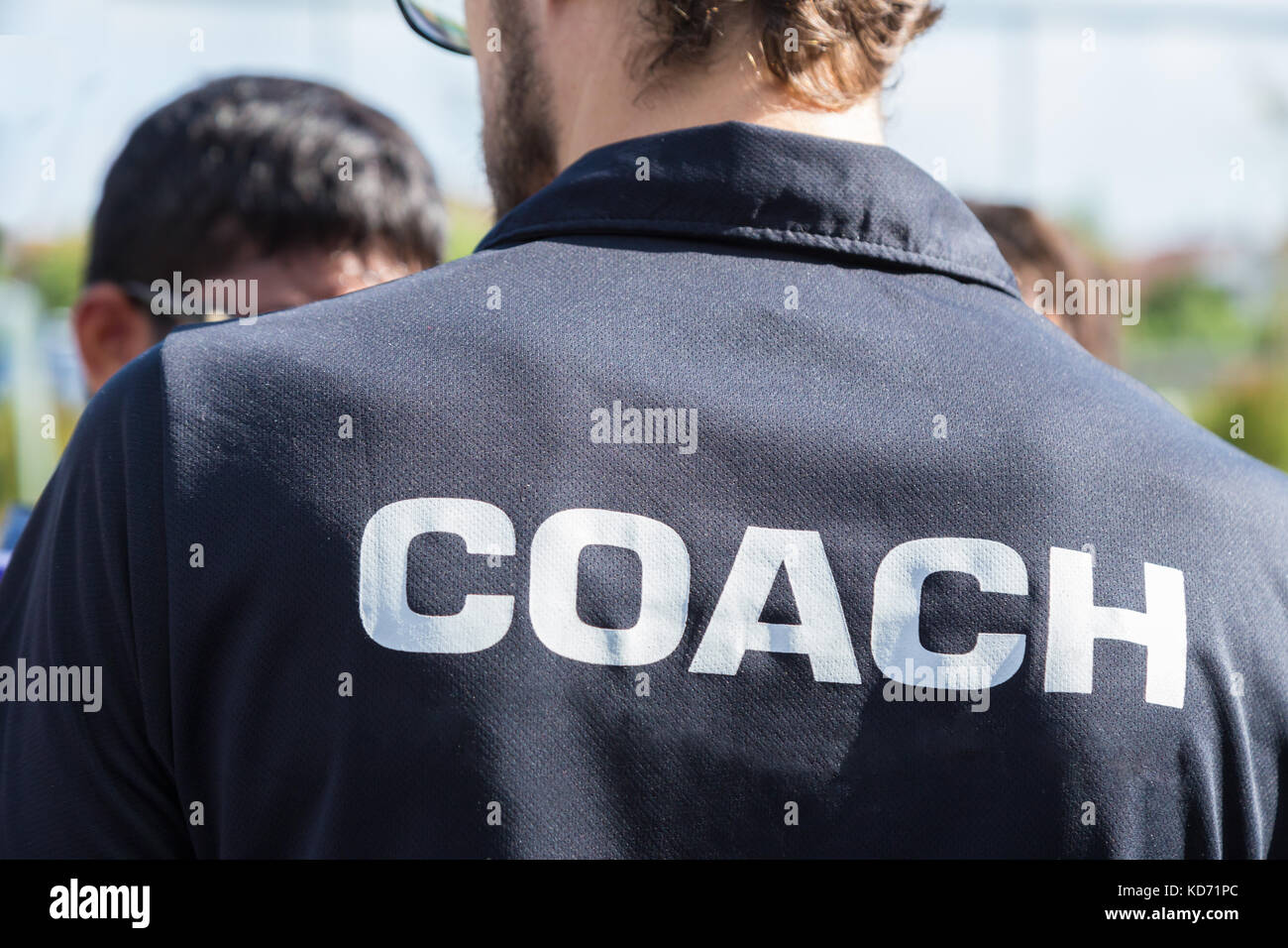 back of a sport coach's black shirt with the white Coach word written ...