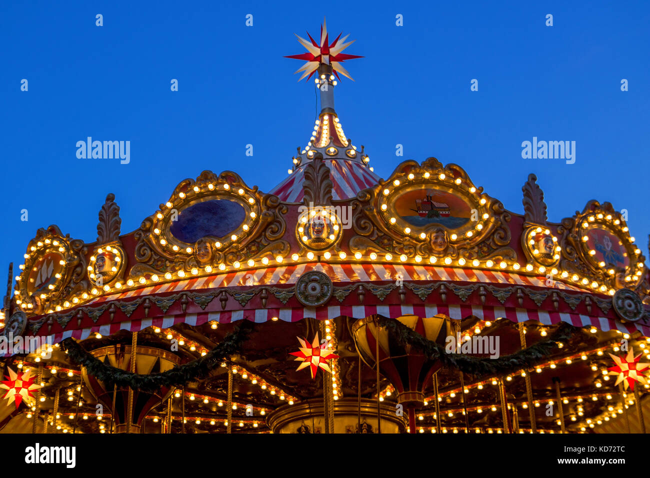 A glowing decoration of carousel on a dark blue sky at dusk. Evening in ...