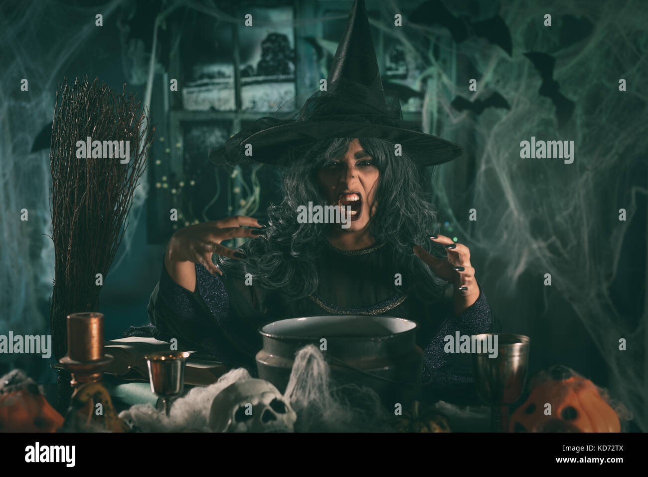 Witch with awfully face and hat on her head in creepy surroundings full ...