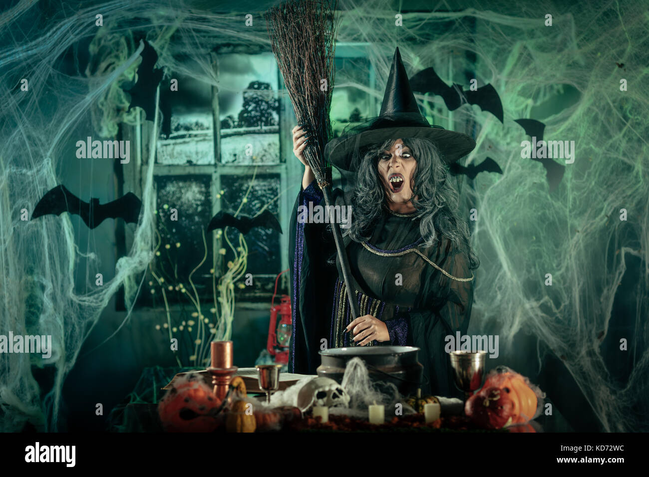 Witch with awfully face and hat on her head in creepy surroundings and ...