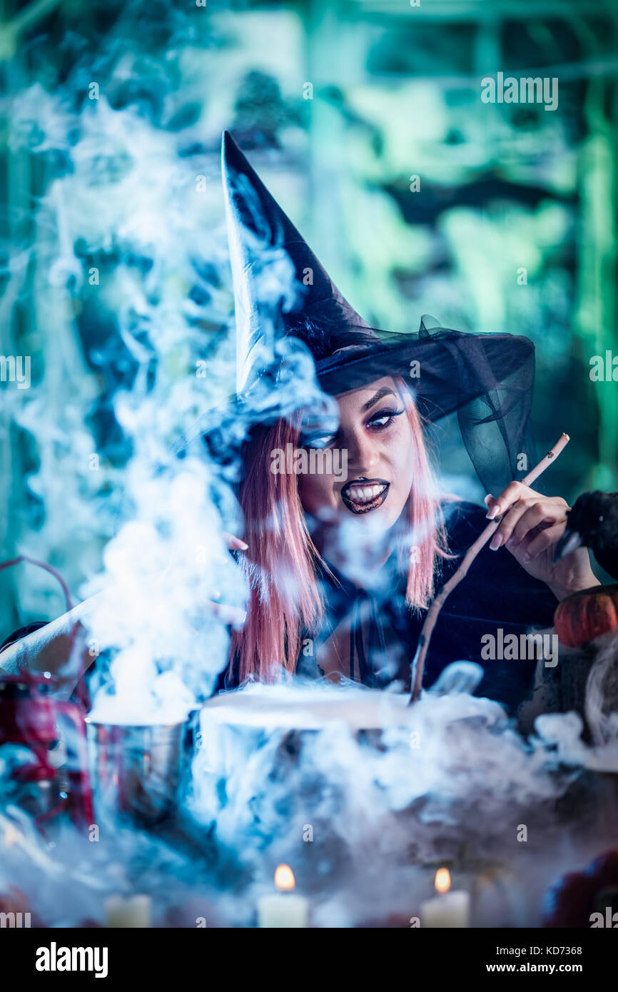 Witch with smiling face in creepy surroundings cooks poison soup in ...
