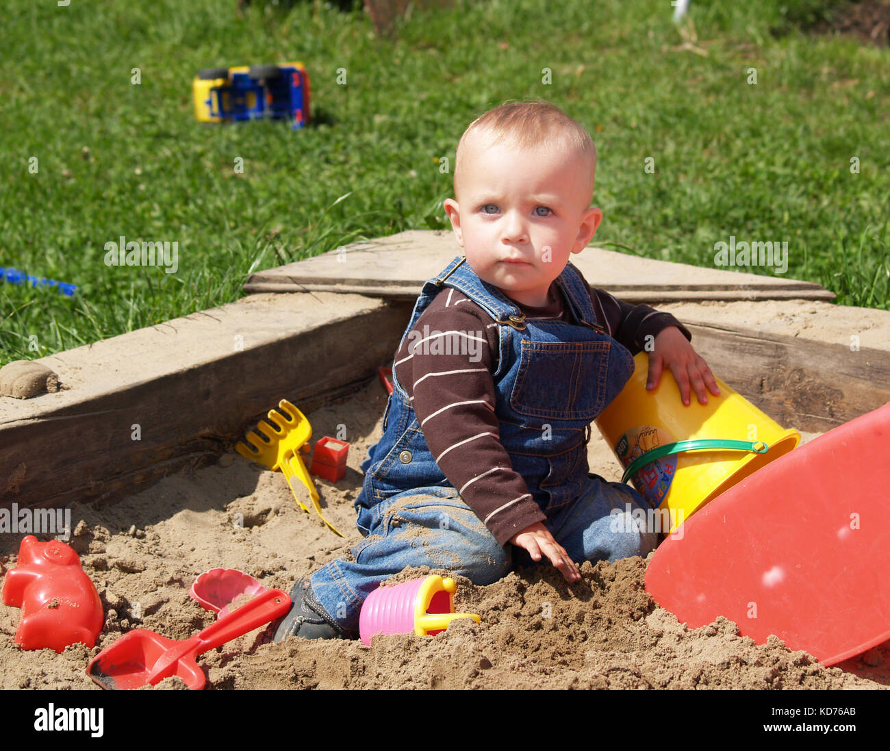 Little girl sitting inside the sand-pit Stock Photo - Alamy