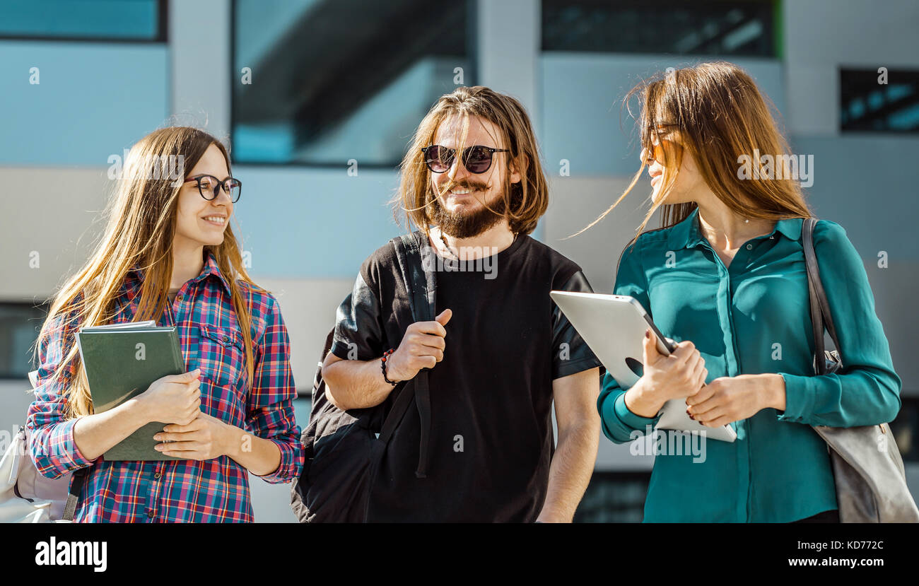 Students colleagues, walk before modern building, have a pleasant talk ...