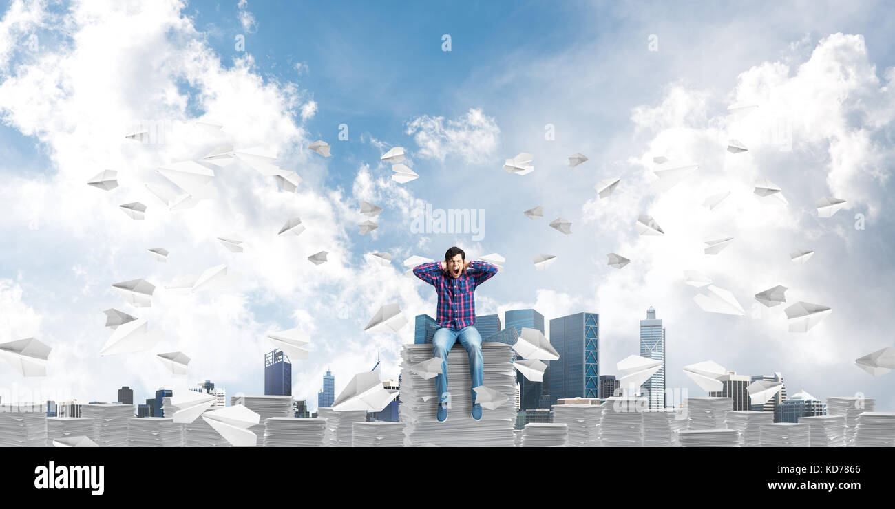Attractive man sitting on pile of paper documents Stock Photo - Alamy