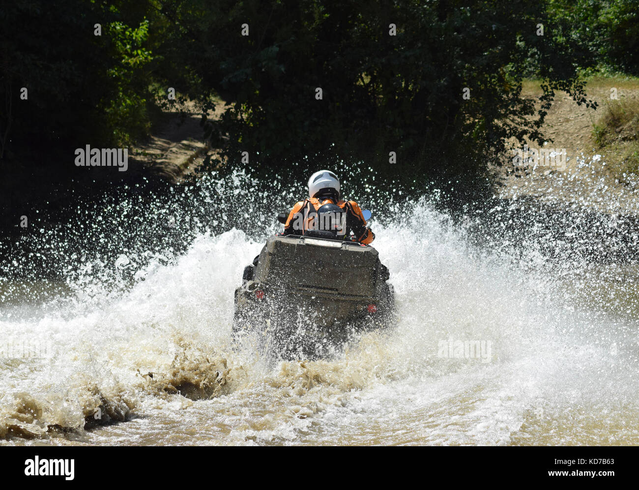 The man on the ATV crosses a stream. Tourist walks on a cross-country ...