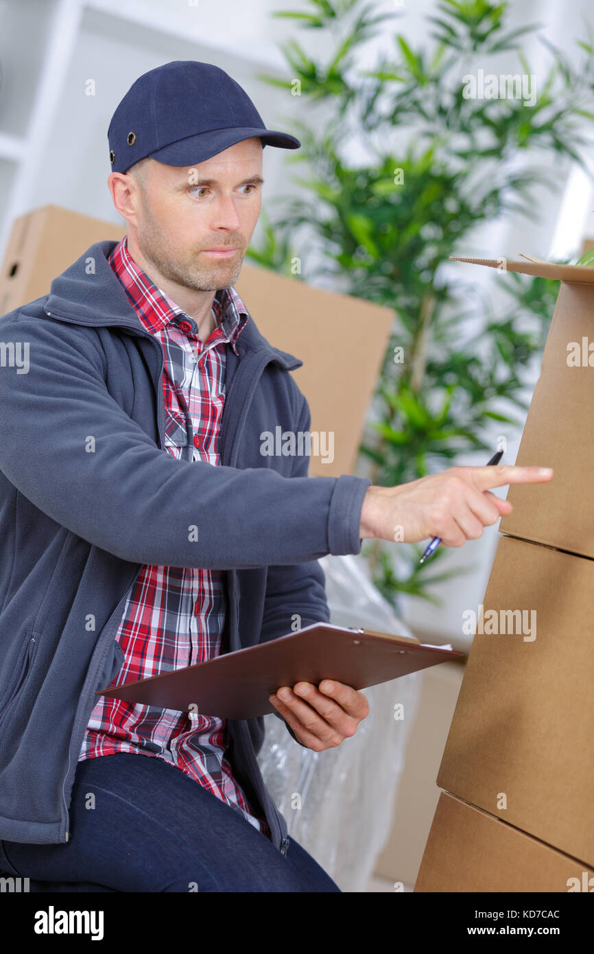 cheerful young man mover holding a cardboard boxes Stock Photo - Alamy