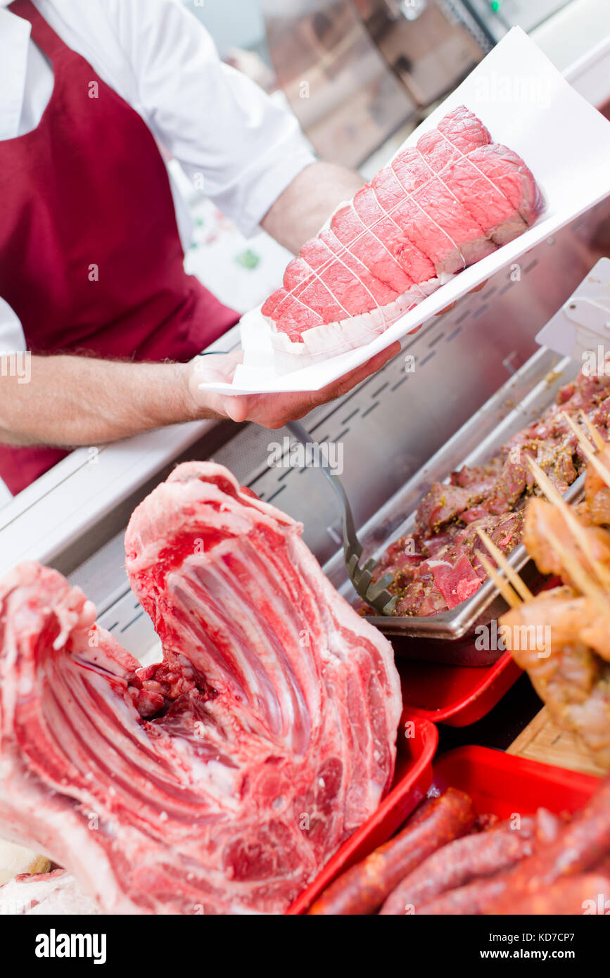 Butcher adding joint of beef to display Stock Photo - Alamy