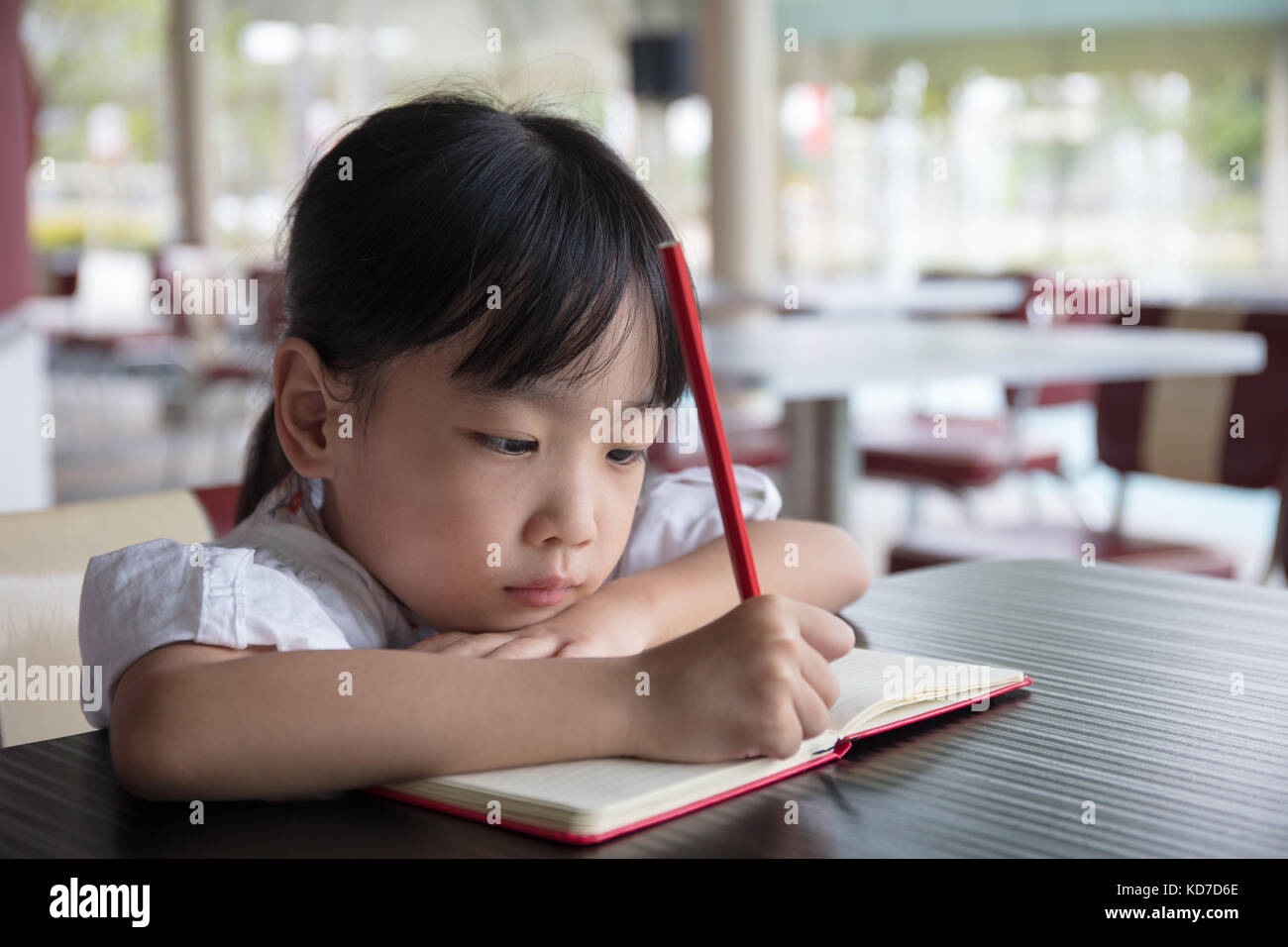 Asian Chinese little girl doing homework at outdoor cafe Stock Photo ...