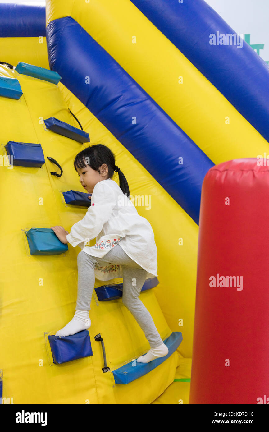 Asian Little Chinese Girl climbing up ramp at Indoor Playground Stock ...