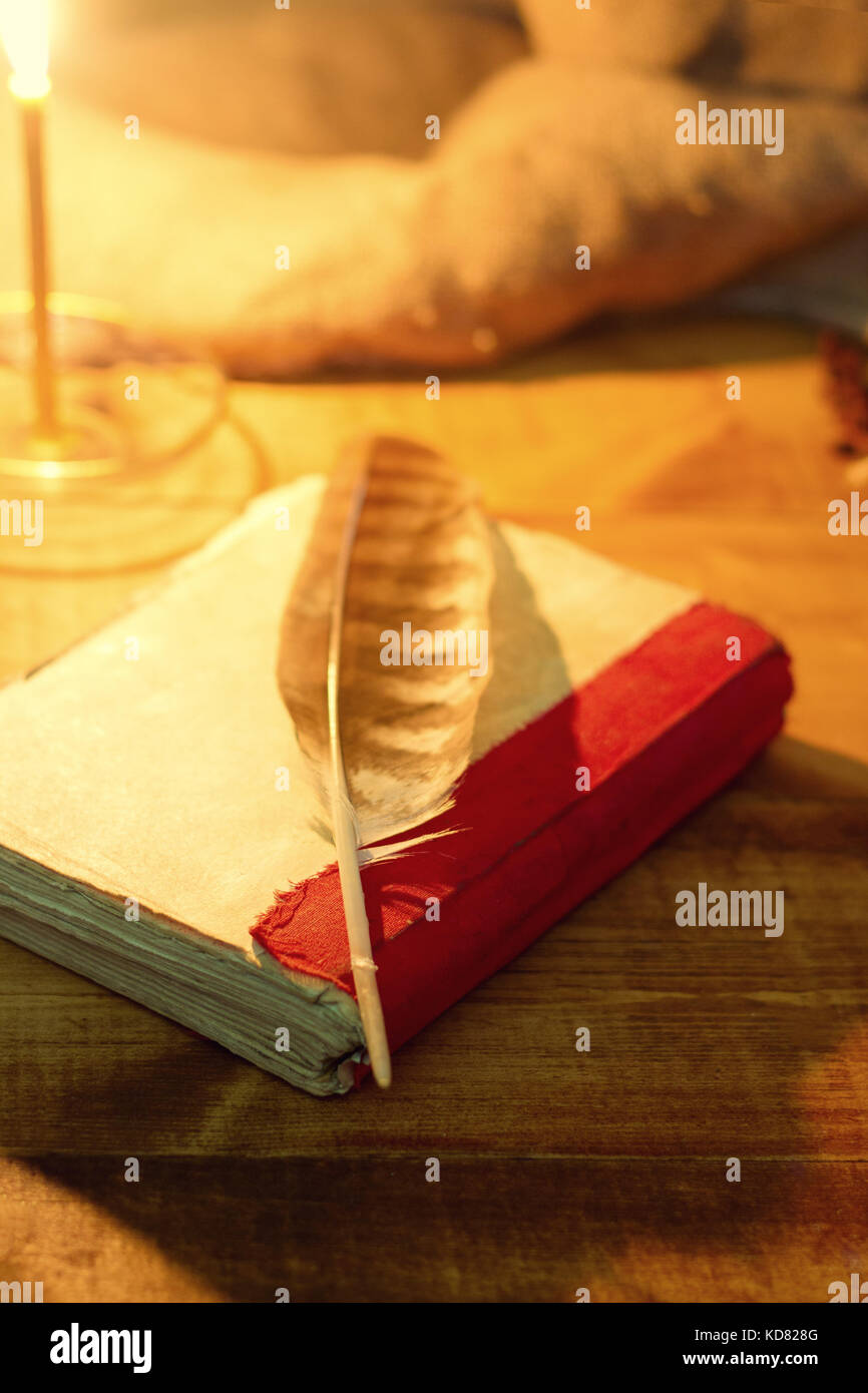 Old book with feather on wooden table Stock Photo - Alamy