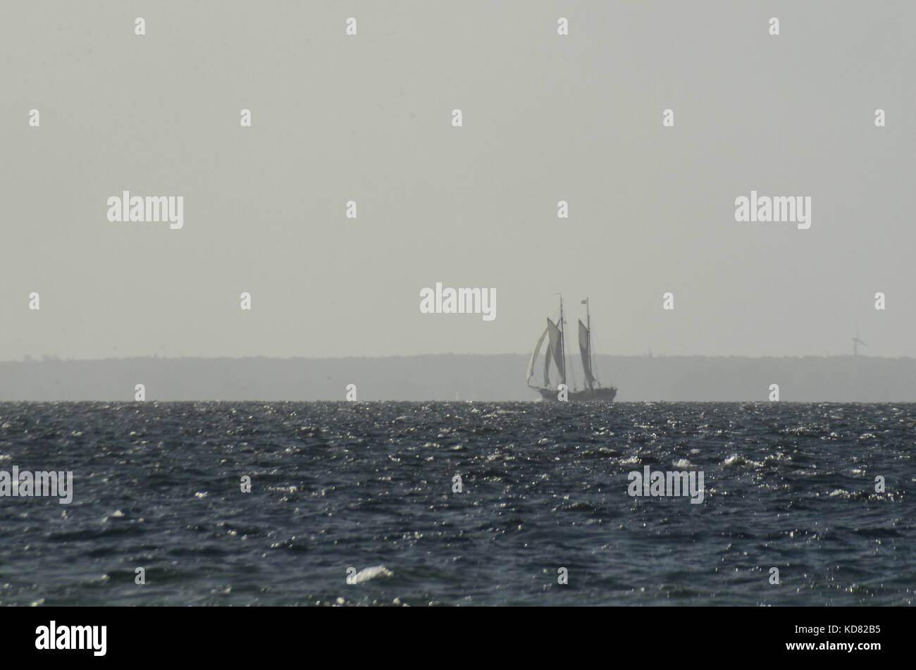 Sea in morning light, with an old sail ship beraking the horizon far ...