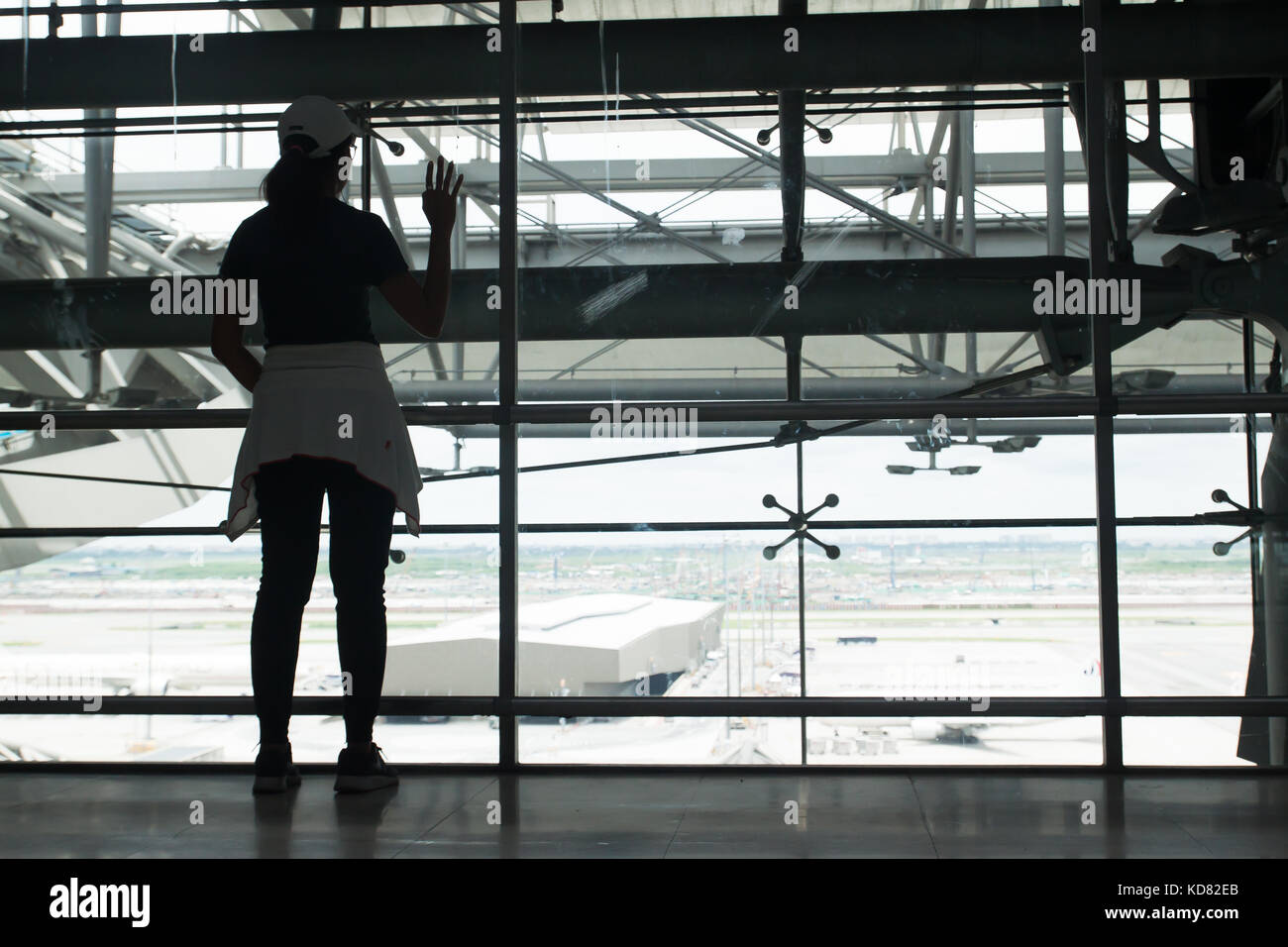 Silhouette of a young woman look out of the window at airport say good ...