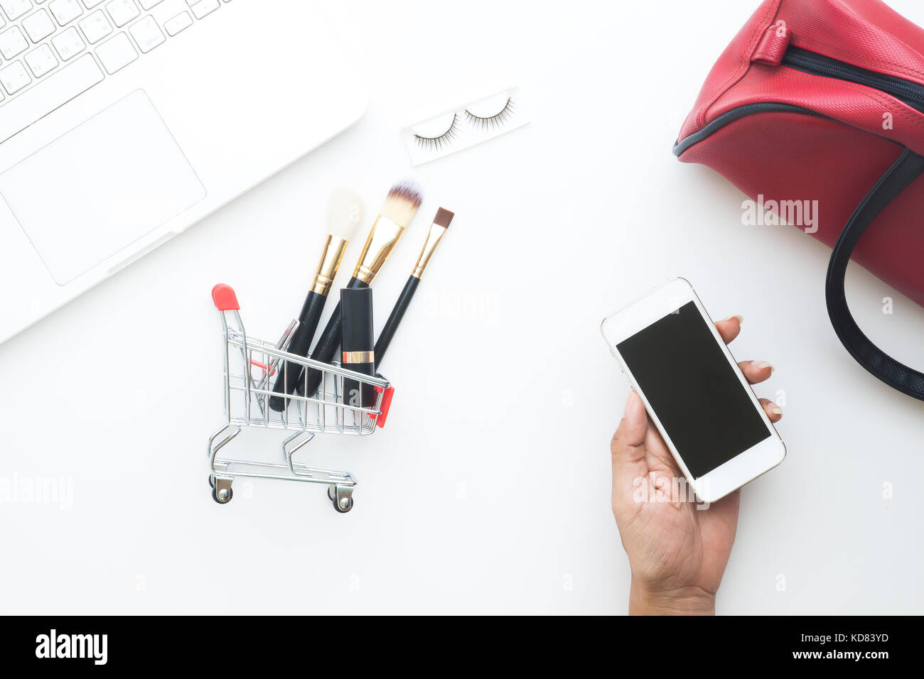 Shopping cart with gift boxes and woman hand holding mobile phone, top ...