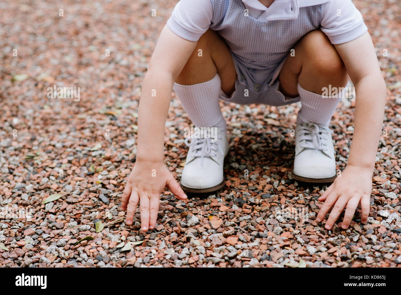 Boy crouching on a gravel driveway Stock Photo - Alamy