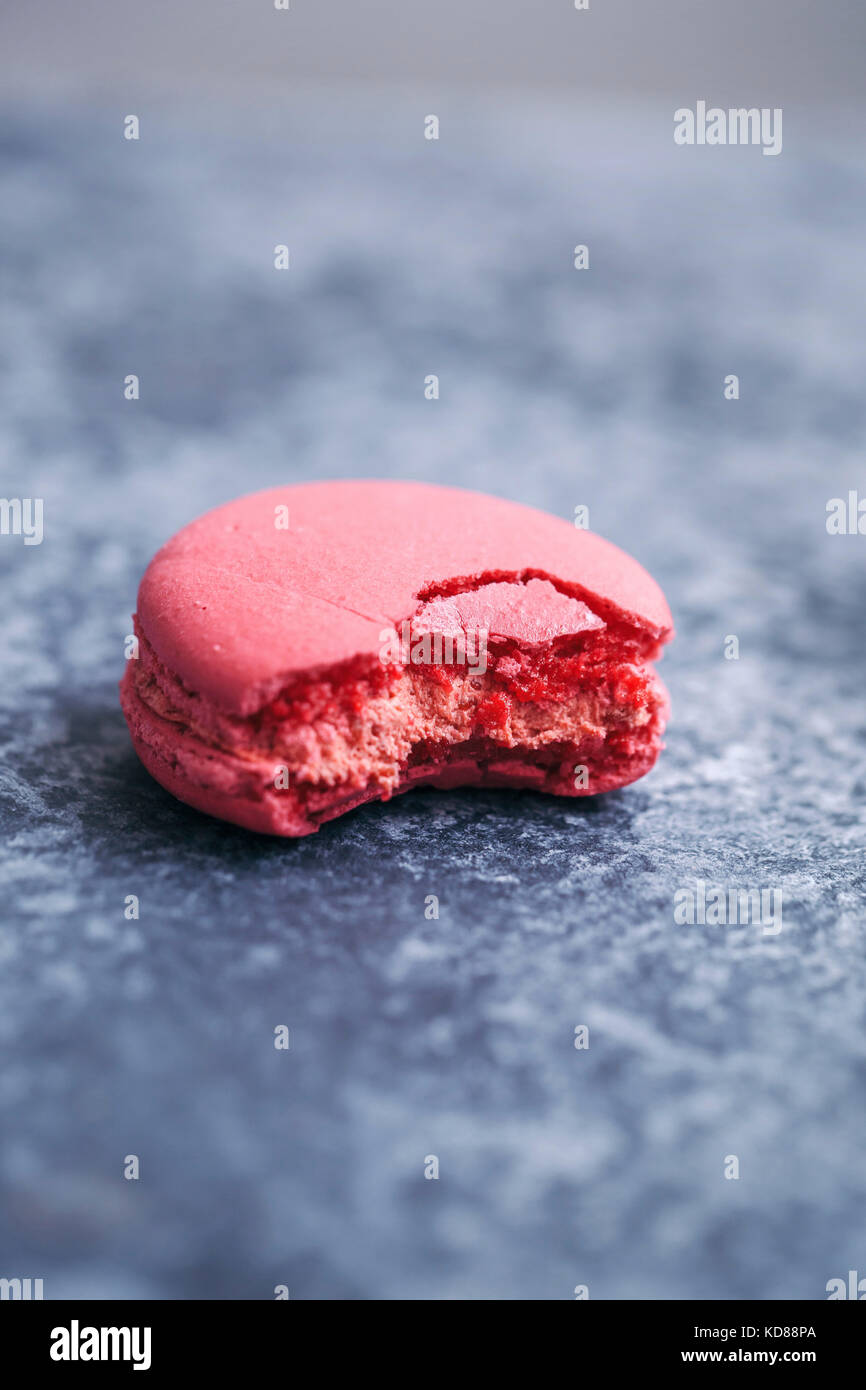 Half eaten pink macaron on grey background Stock Photo - Alamy