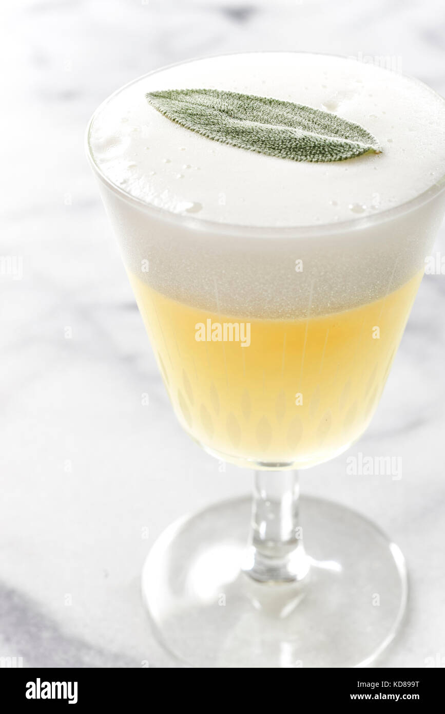 Egg foam cocktail with sage garnish on marble table Stock Photo - Alamy