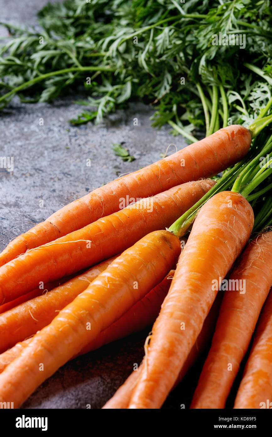 Bundle of fresh organic carrot with haulm over gray texture background ...