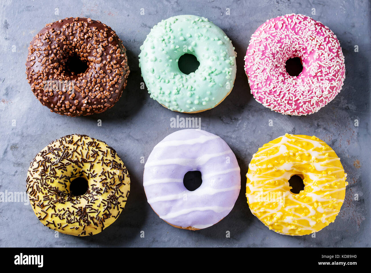 Variety of colorful glazed donuts over gray metal texture background ...